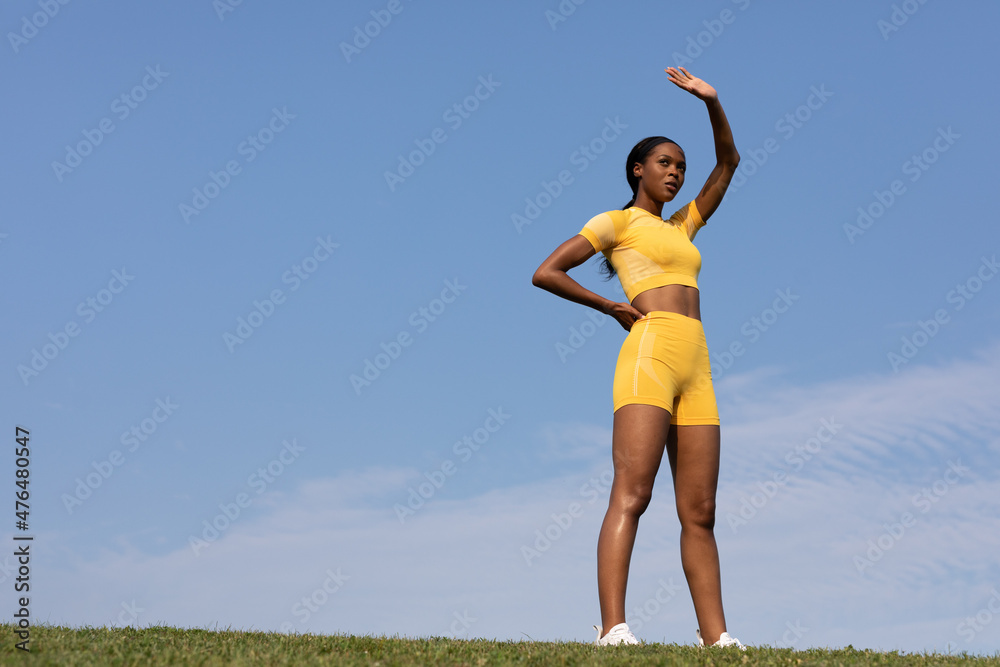 african-American woman in yellow fitness attire during a workout takes ...
