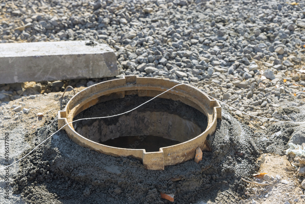 Sewerage construction with utility worker installing underground well ...