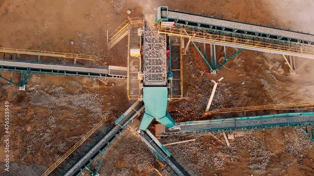 Mining industry concept. Crushed stones falling from a moving line at a ...