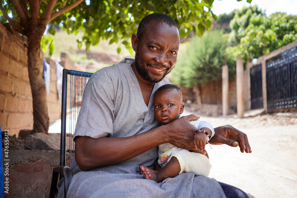 Black African father with his newborn baby in his arms sitting in front ...