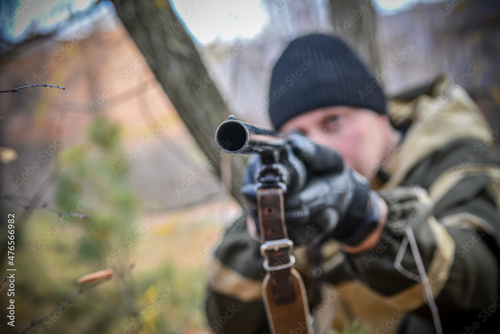 A man aiming with a pump-action shotgun. An armed man fires a shotgun ...