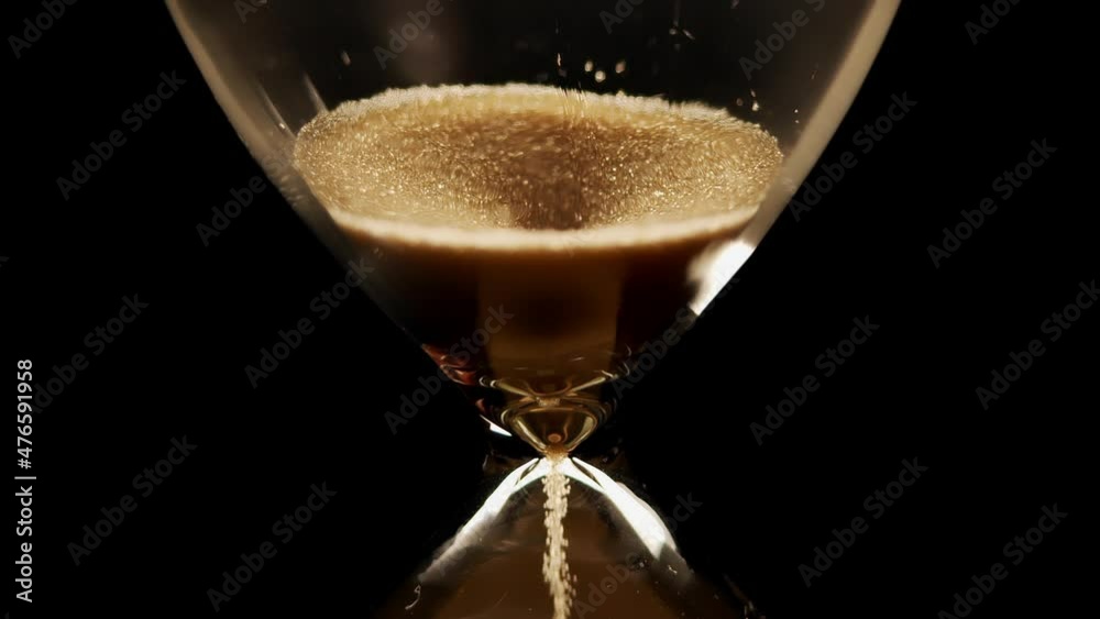 Hourglass. Sands move through hour glass. Sandglass close-up on a black ...