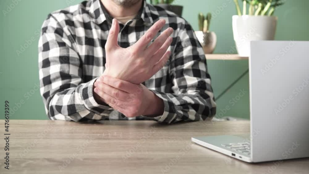 A man suffering from joint pain in his hand and wrist while working at ...