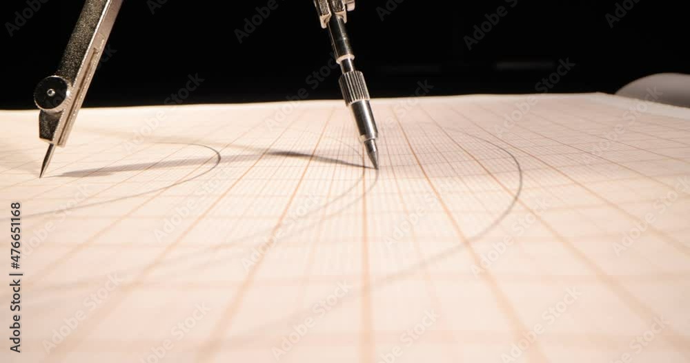 Macro of the compass drawing a circle on paper. Close up, side-view ...