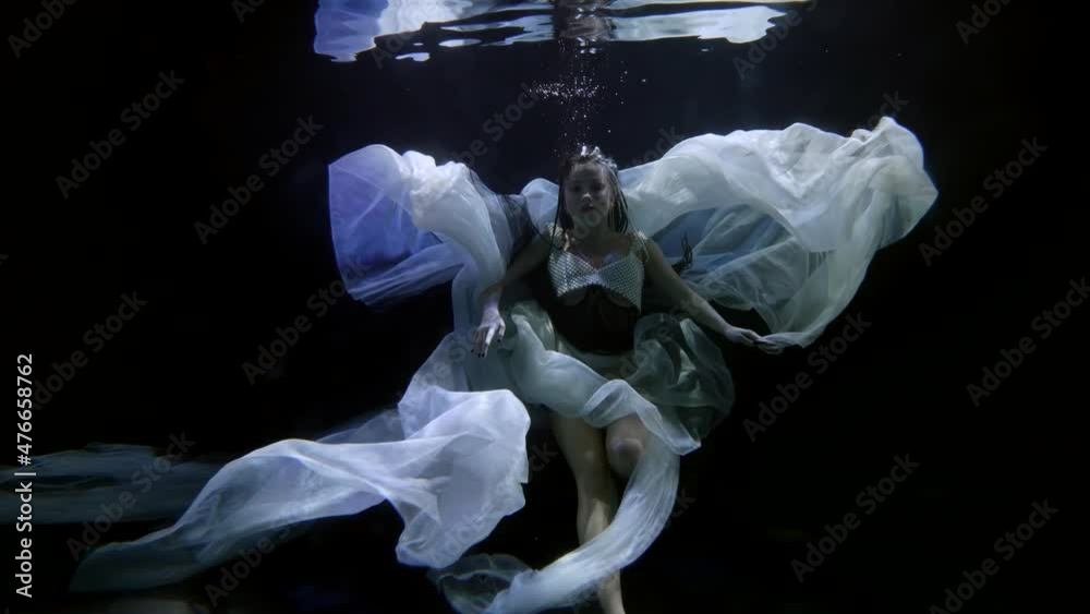 romantic stunning woman in white dress is floating underwater ...