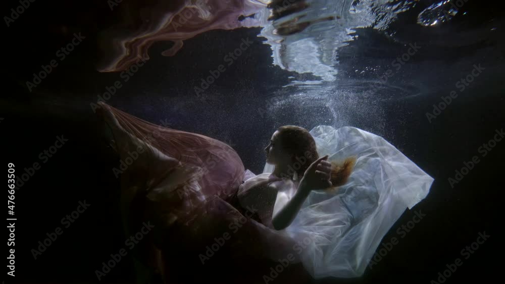 mysterious woman is floating underwater, graceful female figure inside ...