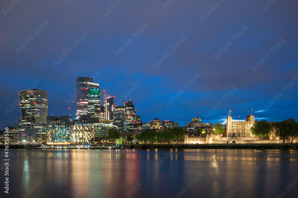 The Tower of London, with the City of London skyscrapers behind it. Lit ...