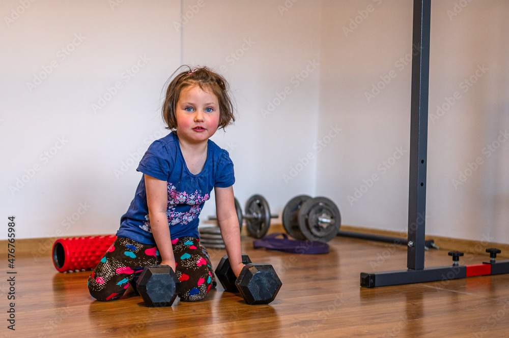 A four-year-old girl is doing calisthenics workout in home gym. Stock ...