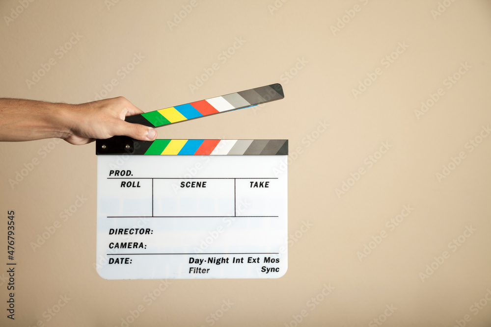 Hands holding movie clapper board on neutral background. With ...