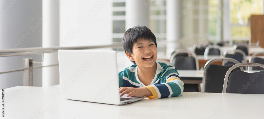 Portrait of Cute Asian boy studying or playing game with laptop ...