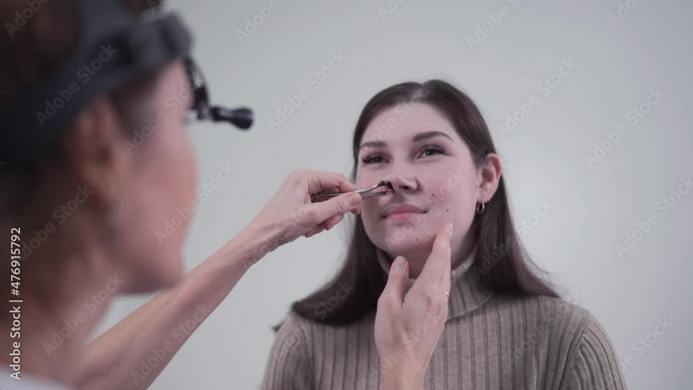 Female ENT doctor examines patient's sinuses with medical instrument in ...