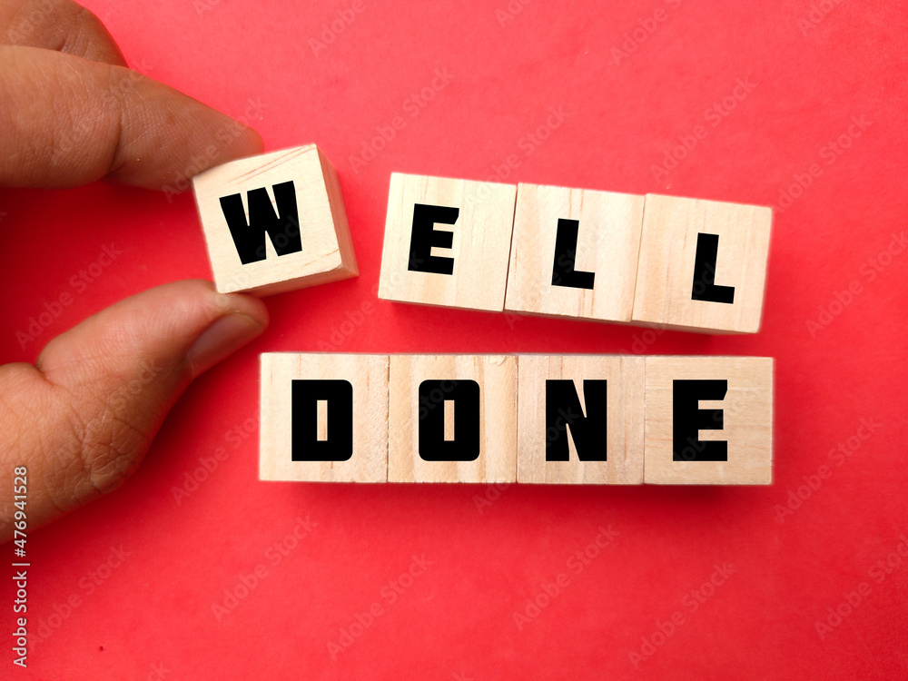 Hand holding wooden cube with text WELL DONE on a red background. Stock ...