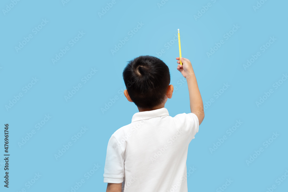 Kid hoding pencil and pointing upwards wearing white shirt, back view ...