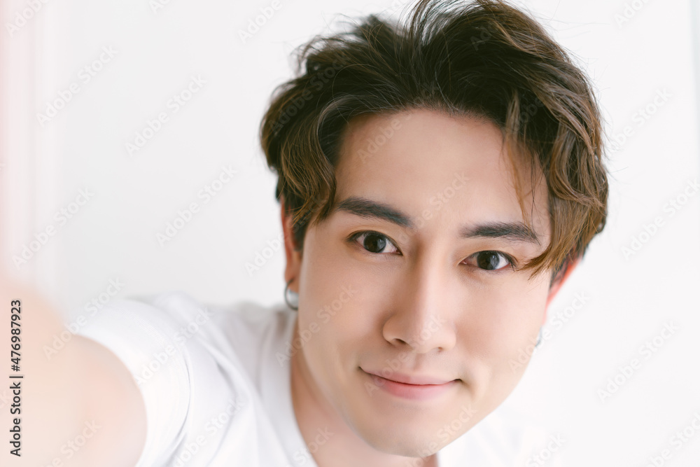 Closeup of beautiful young Asian man in casual clothes taking selfie ...