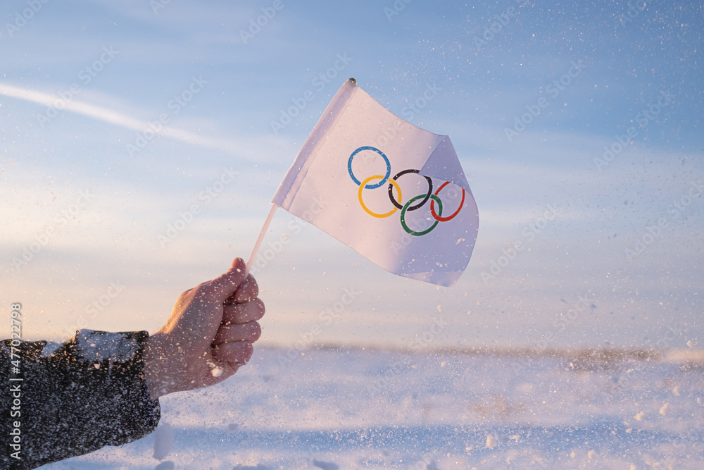 The Olympic flag, small in hand, flutters against the backdrop of snow ...