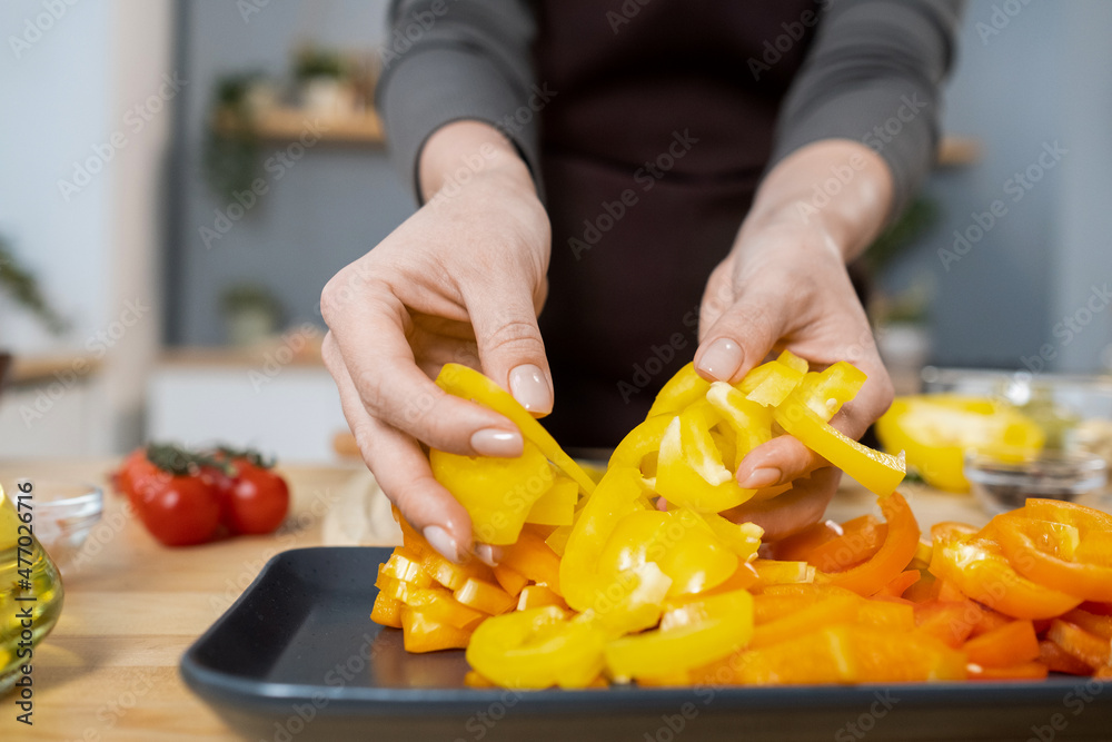 Hands of female putting chopped fresh yellow capsicum on tray while ...