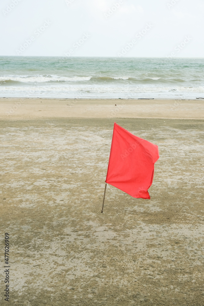 Selective focus picture of waving red flag at the beach with strong ...