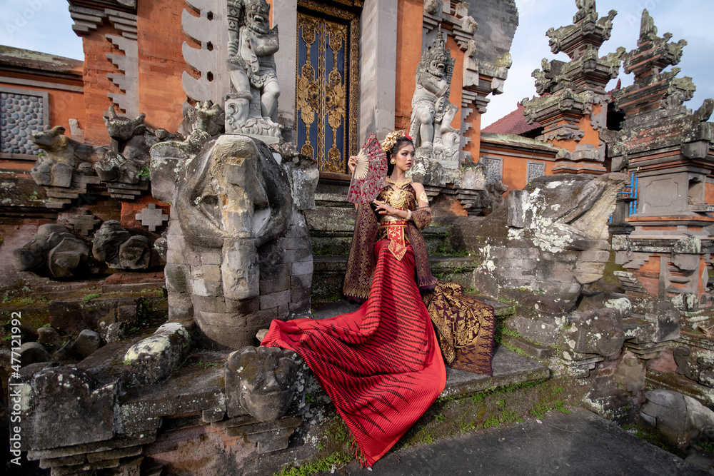 Beautiful balinese girl in traditional costume with a flower and a ...