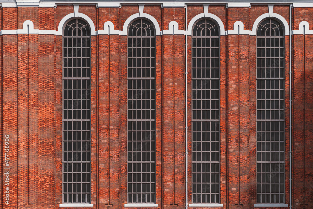 A reddish masonry wall with long gray windows. A red brick facade ...