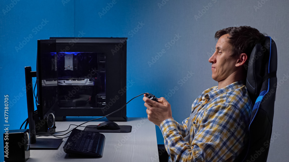 Young dark-hired man plays videogame tensely on large computer screen ...