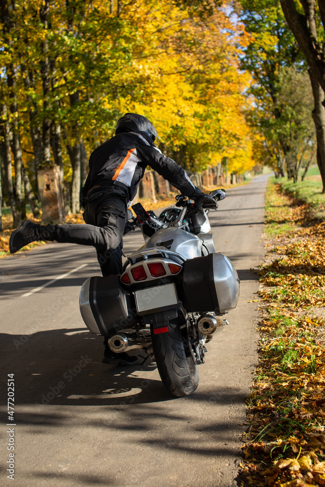 Young male motorcycle getting on a motorcycle, rear view, helmet for ...