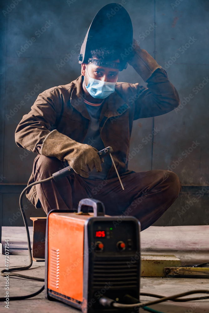 The welder welds metal structures by manual electric arc welding. MMA ...