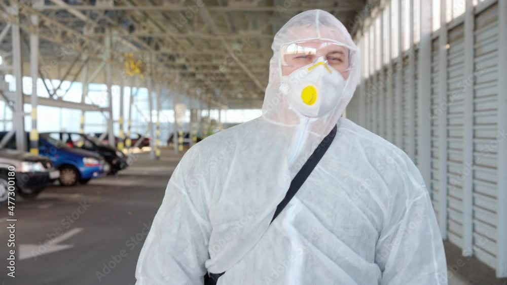 Man dressed protective overalls walk parking. Disinfectant walking with ...