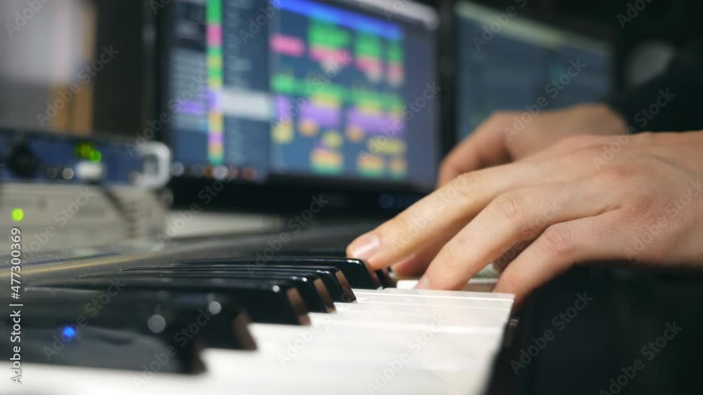 Hands of male musician playing at synthesizer at sound recording studio ...