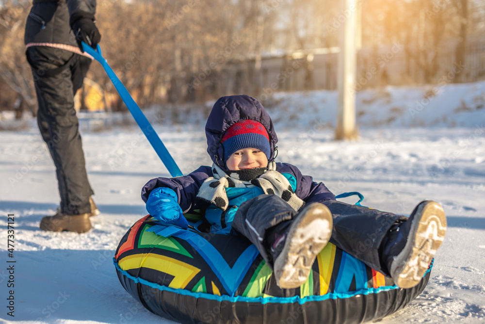 A happy child with his mother is tubing with a park from a slide. A fun ...