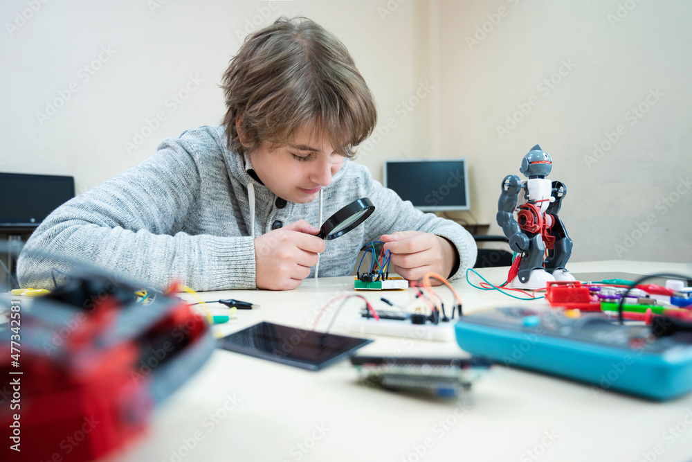 Teenager boy at robotics school makes robot managed from the ...