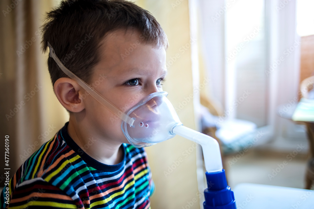 Child holds a mask vapor inhaler. Sick Caucasian boy using inhaler ...