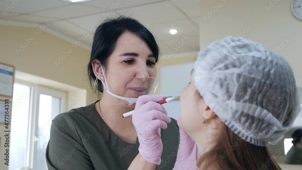 The permanent makeup artist draws a contour sketch of the future lips ...