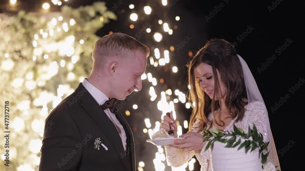 Newlyweds cut the wedding cake with knife. Fireworks. Lovely bride and ...