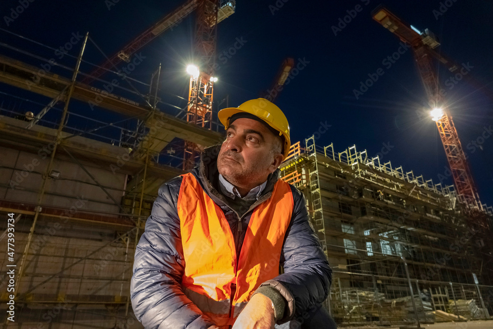 Construction worker sitting beside a building under construction at ...