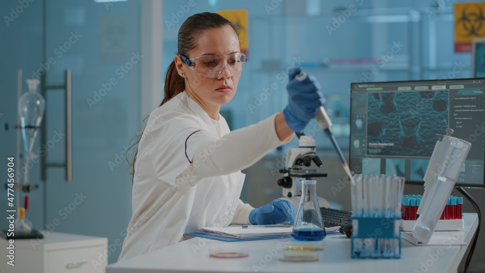 Woman biologist using micro pipette with test tube and beaker for ...