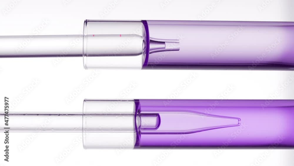 Lab dropper takes purple liquid from test tube and drips it back in ...