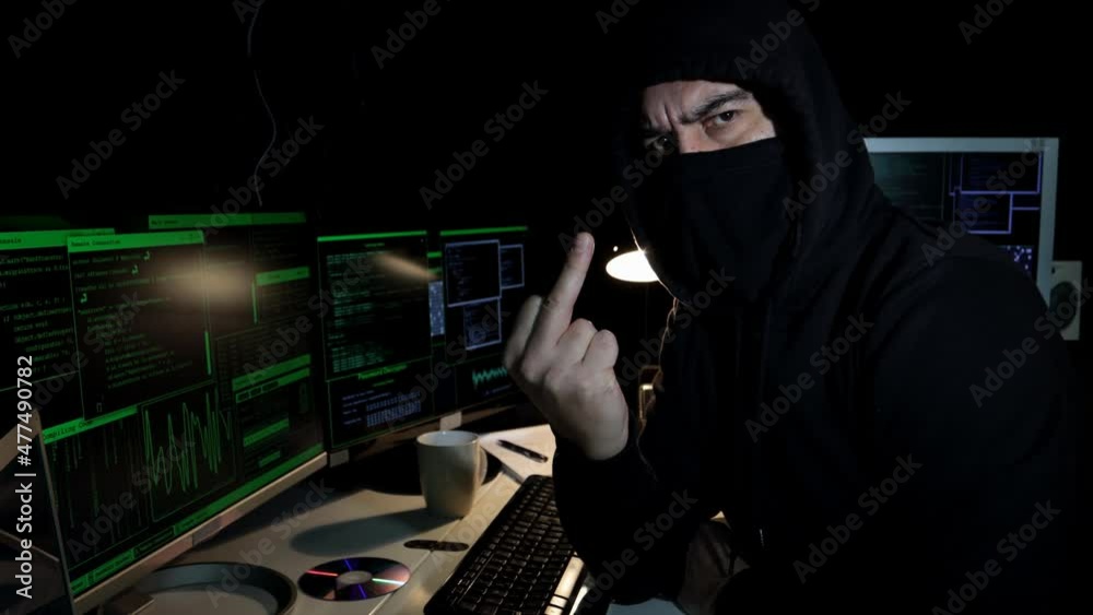 Cyber hacker with hood and covered face looks at the camera showing ...