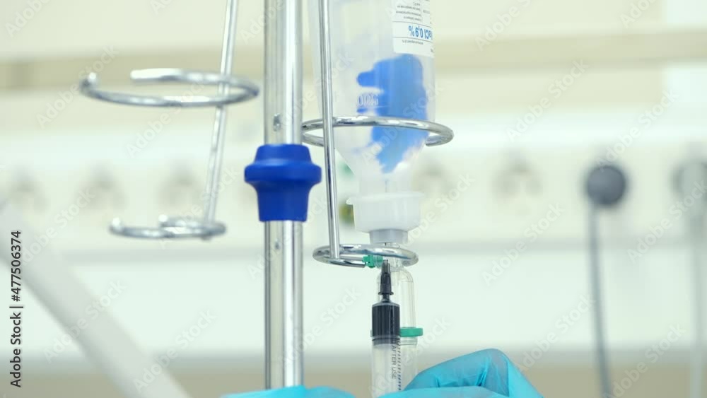 Close-up of hospital drip with injection. Action. Blue powder is ...
