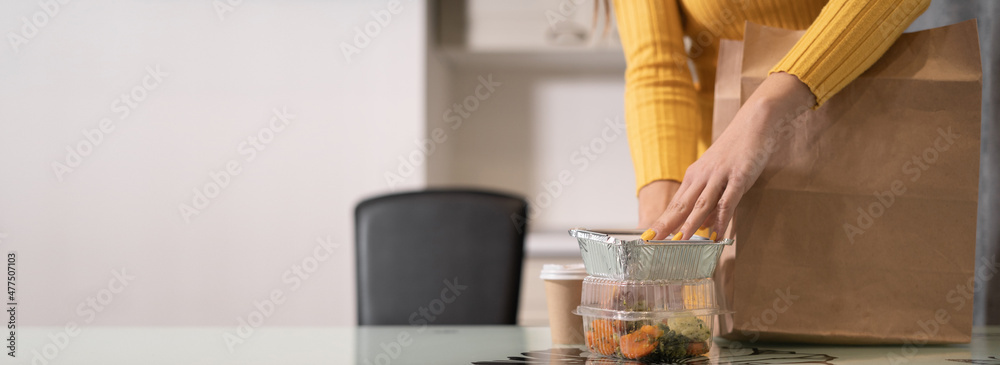 Close-up of female hands take out food in disposable trays from a paper ...