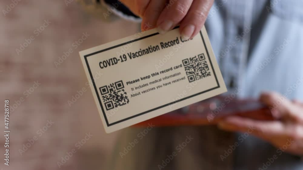 A woman shows her Covid 19 vaccination card with QR code that is her ...
