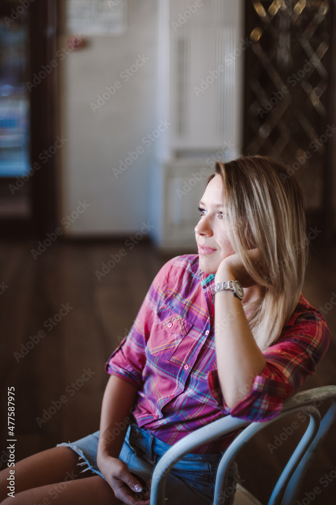 Adult shining blonde woman with face looking away, sitting on chair in ...