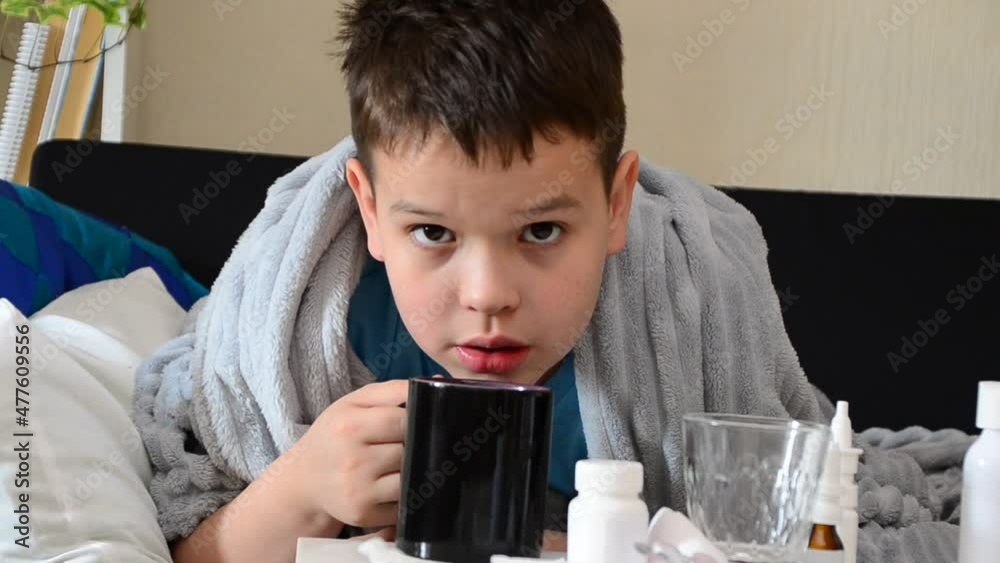 Sick child boy lying in bed with a fever, resting at home. a boy with a ...