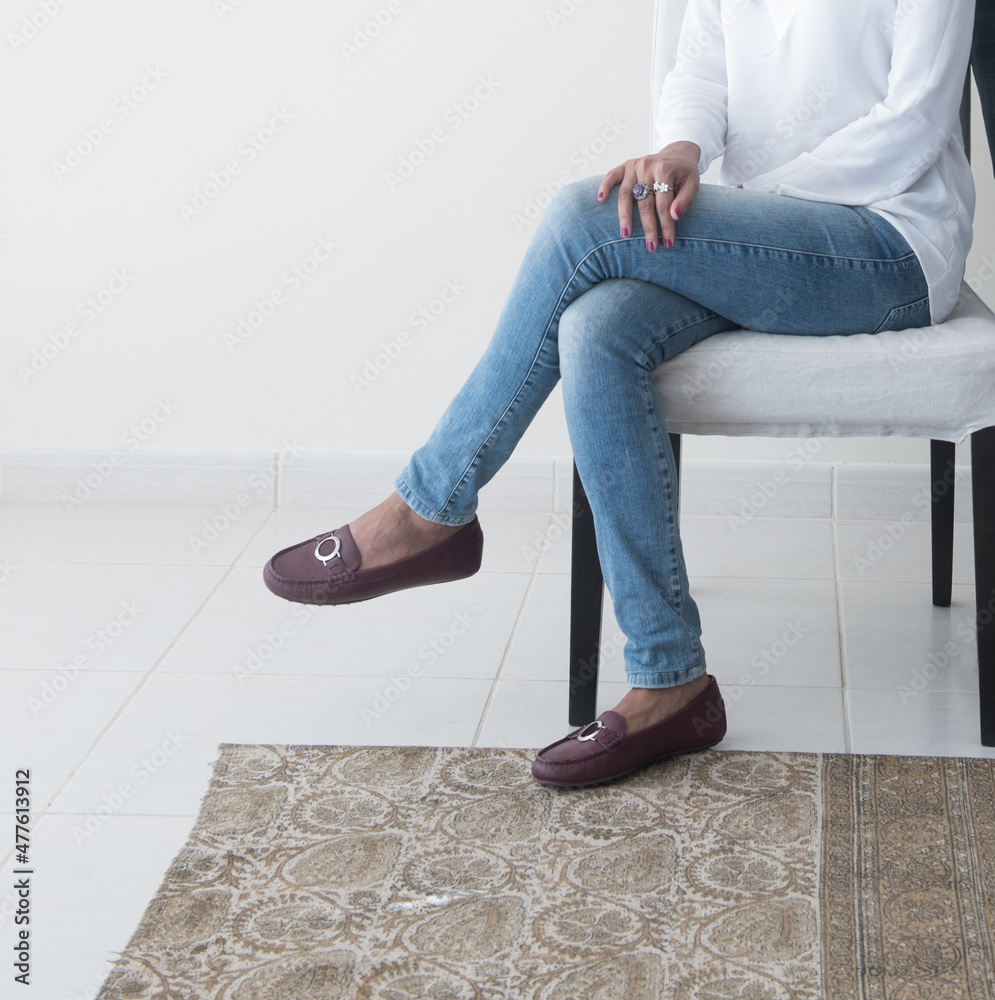 Partial view of a lady sitting with folded legs. A modern woman with ...