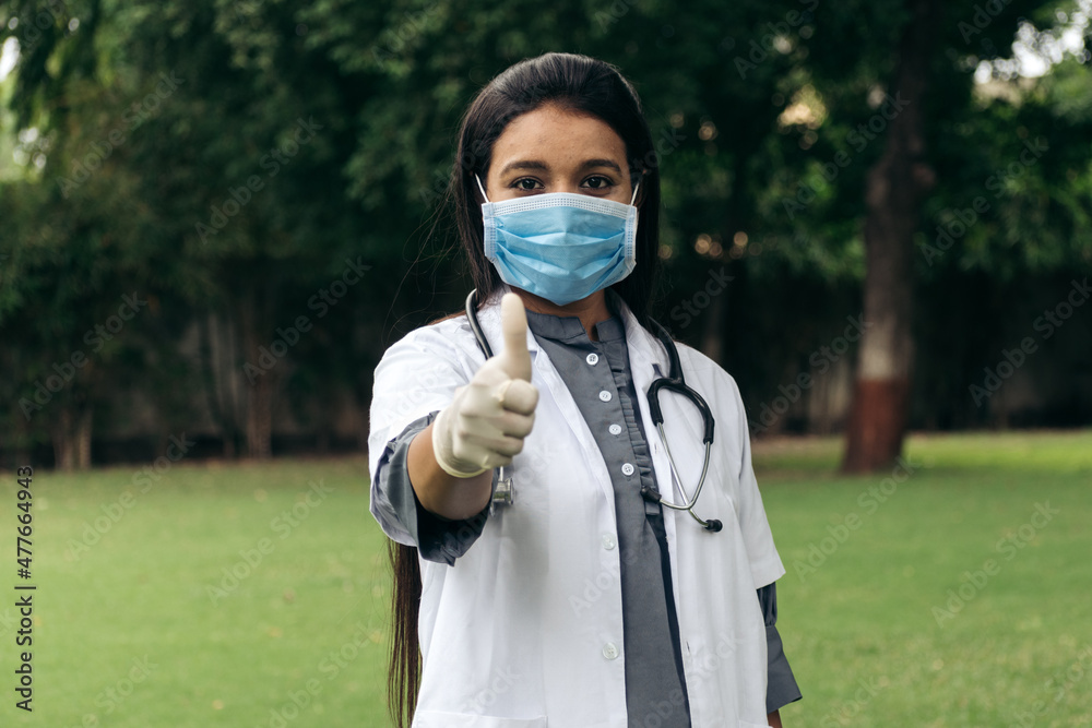 Portrait of positive Indian female doctor wearing mask and giving ...