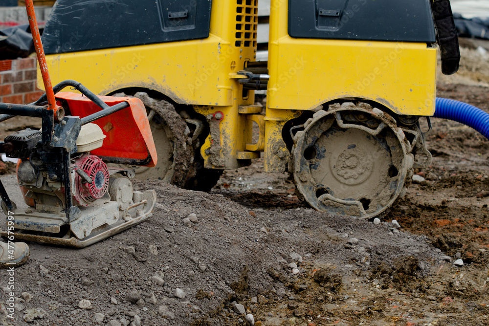 Construction worker using petrol powered plate compactor to compact ...
