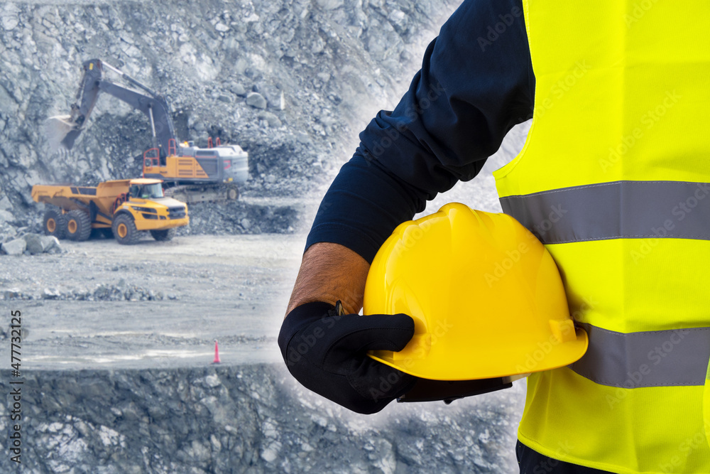 A worker holds a construction helmet in his hand against the background ...
