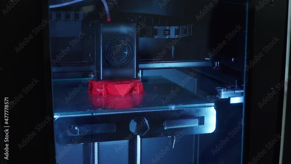 3D printer prints a red model. the plastic toy factory uses modern ...