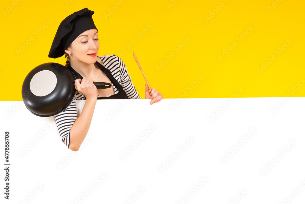 Woman cook in black apron. She is holding frying pan in her hands ...