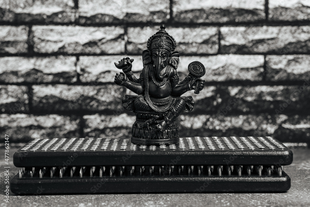 Stone statue of Lord Ganesha, hindu God.Close-up black Sadhu wooden ...