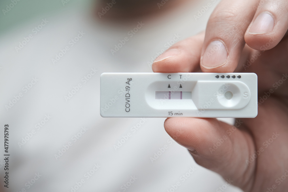 Close-up of a hand holding a positive antigen test for COVID-19. Stock ...